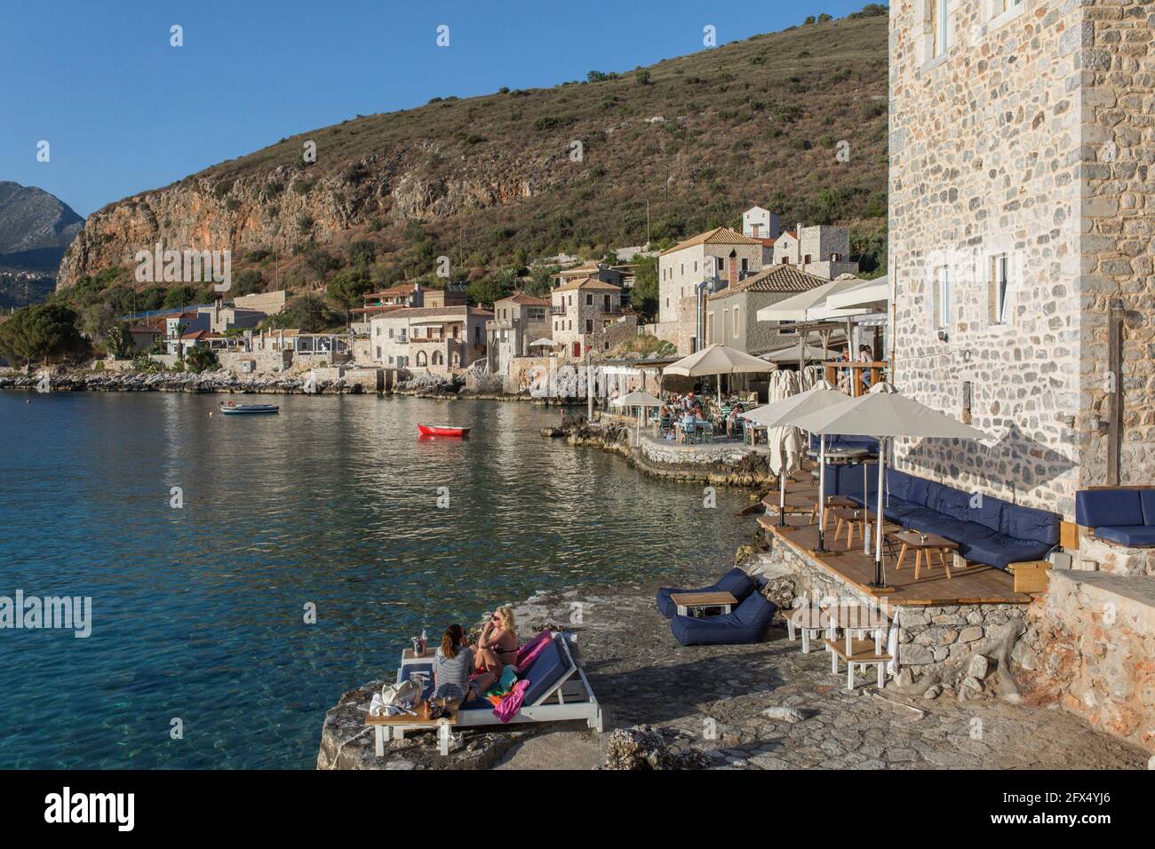 Limeni, Greece. 23rd May, 2021. Tourists sit in a café by the sea in ...