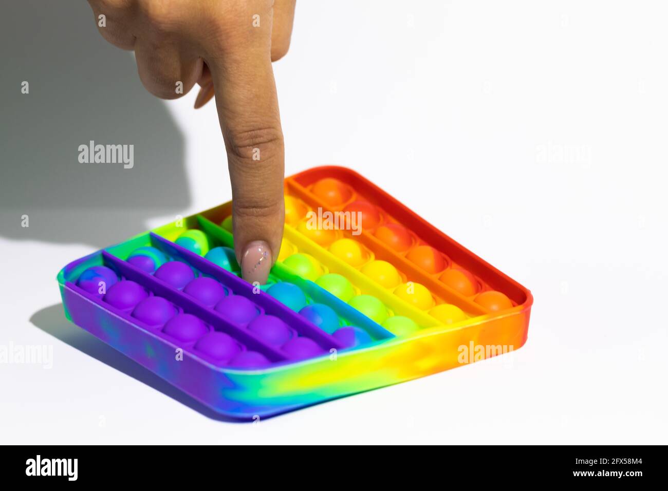 Pop It Fidget toy, female hand push bubbles on rainbow game, white ...