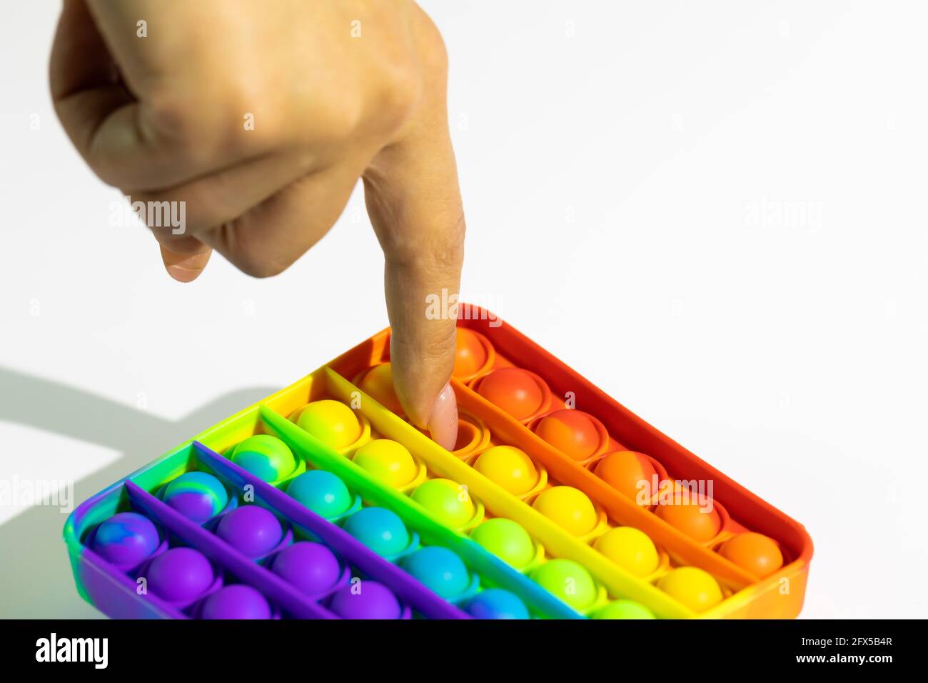 Pop It Fidget toy, female hand push bubbles on rainbow game, white ...