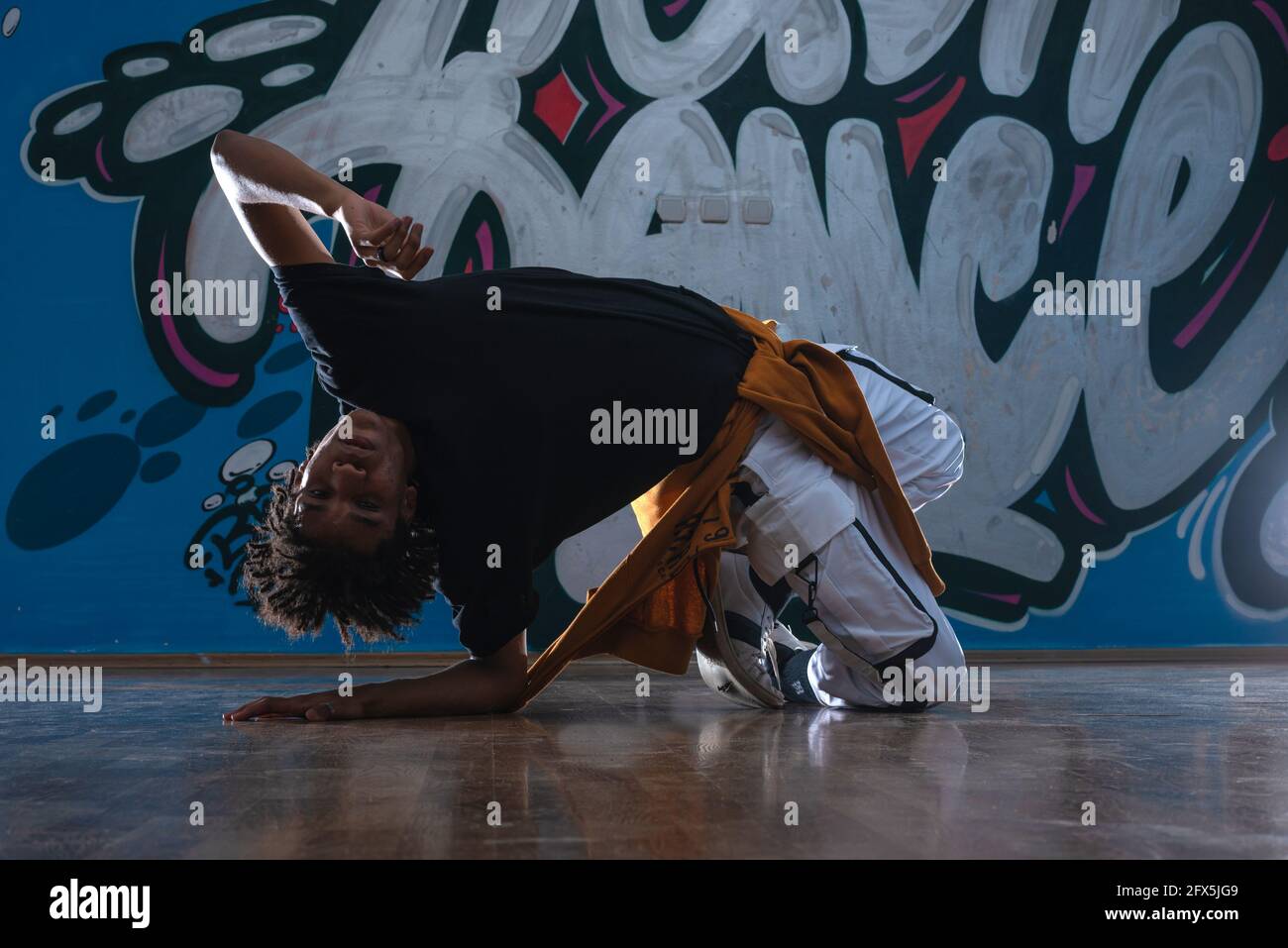African American hip hop dancer (breakdancer) performing over graffiti ...