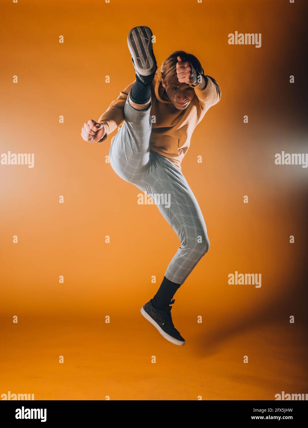 Caucasian male dancer exercising a contemporary dancing on orange wall ...