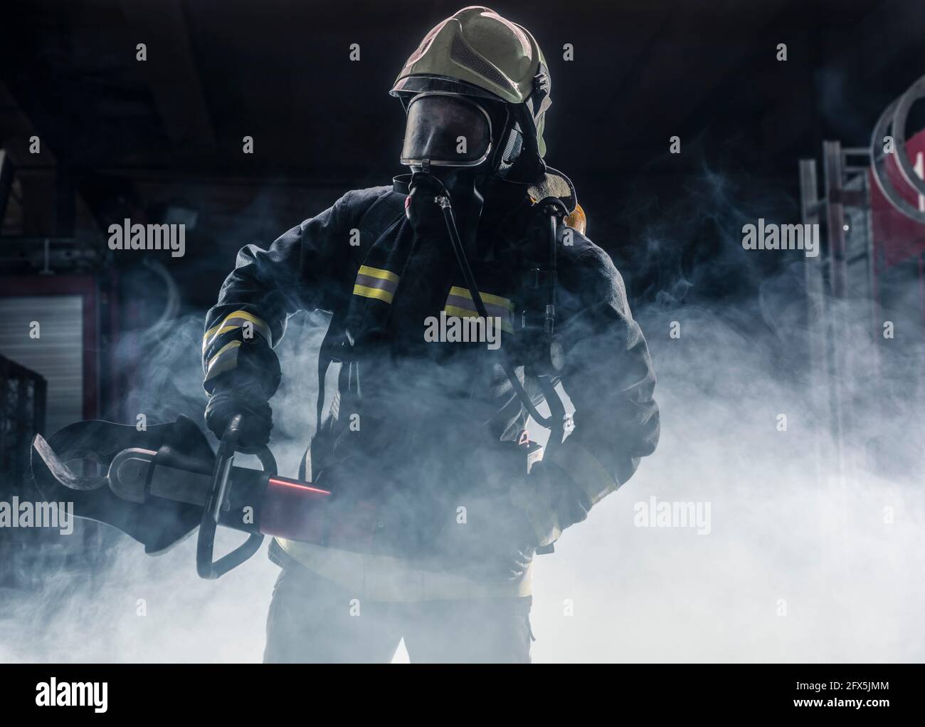 Portrait of a fireman wearing firefighter turnouts and helmet. Dark ...