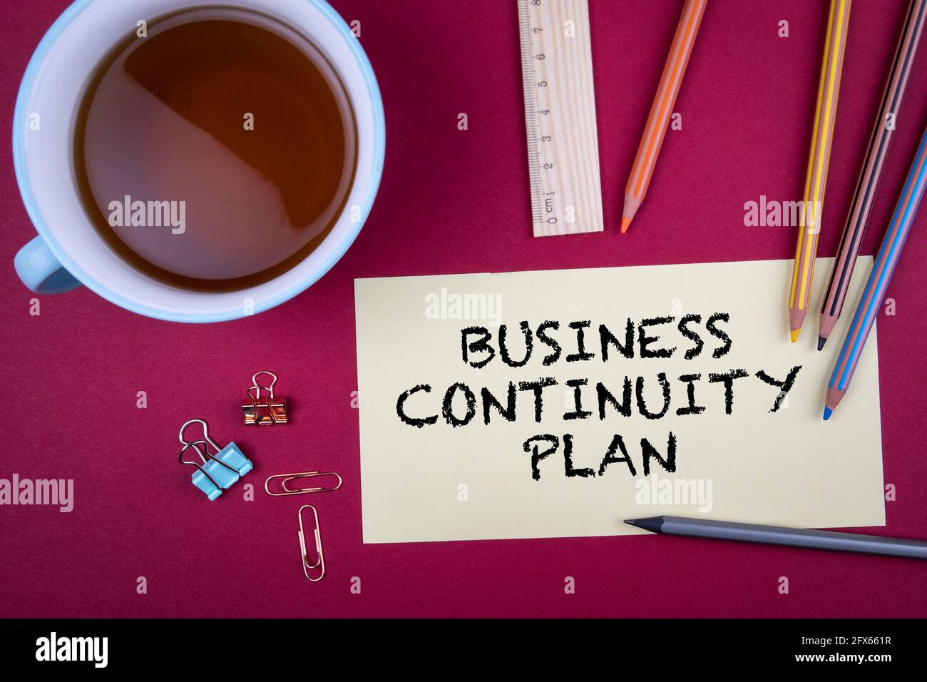 BUSINESS CONTINUITY PLAN. Note sheet and office supplies on a red ...