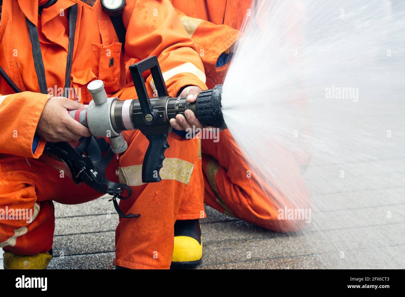 Firefighters spray water Stock Photo - Alamy