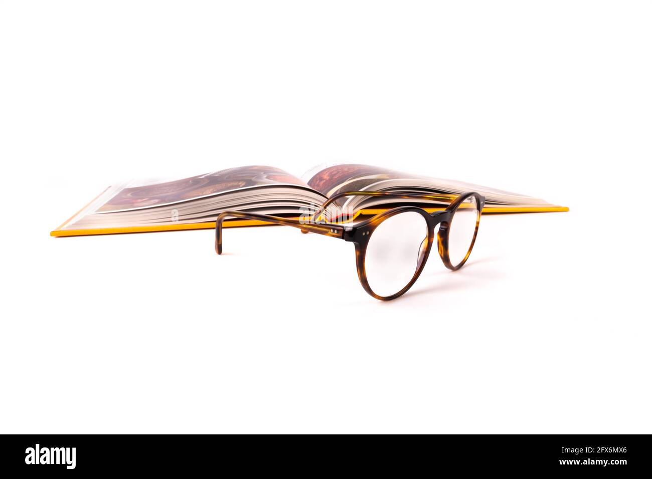 Open book with reading glasses close-up isolated on white background ...