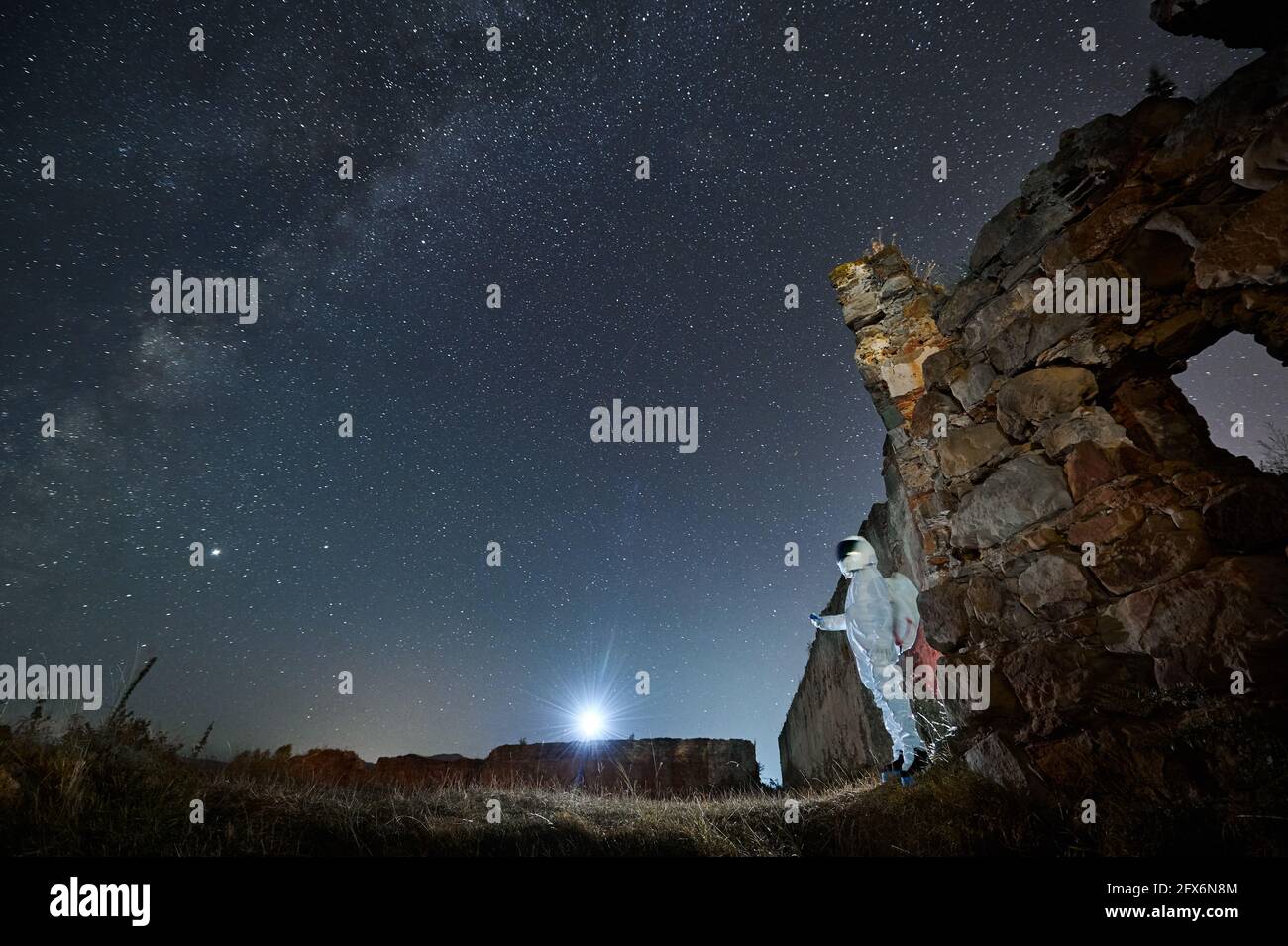 Side view of spaceman in white suit and helmet looking on starry sky ...