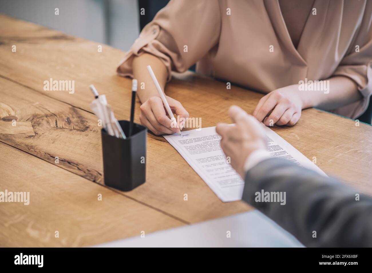 Woman hand signing document and male pointing Stock Photo - Alamy