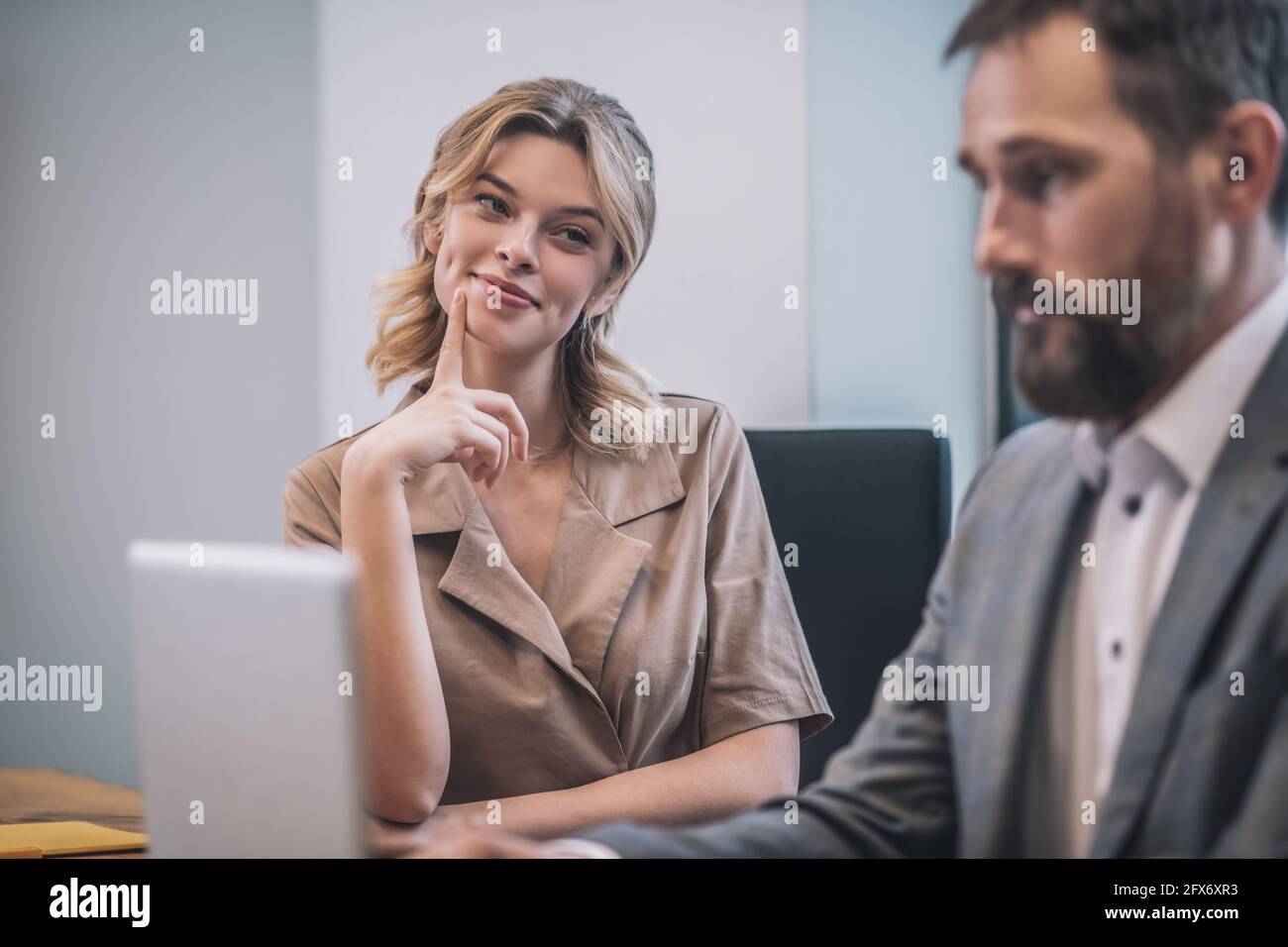 Smiling pretty woman looking at serious busy boss Stock Photo - Alamy