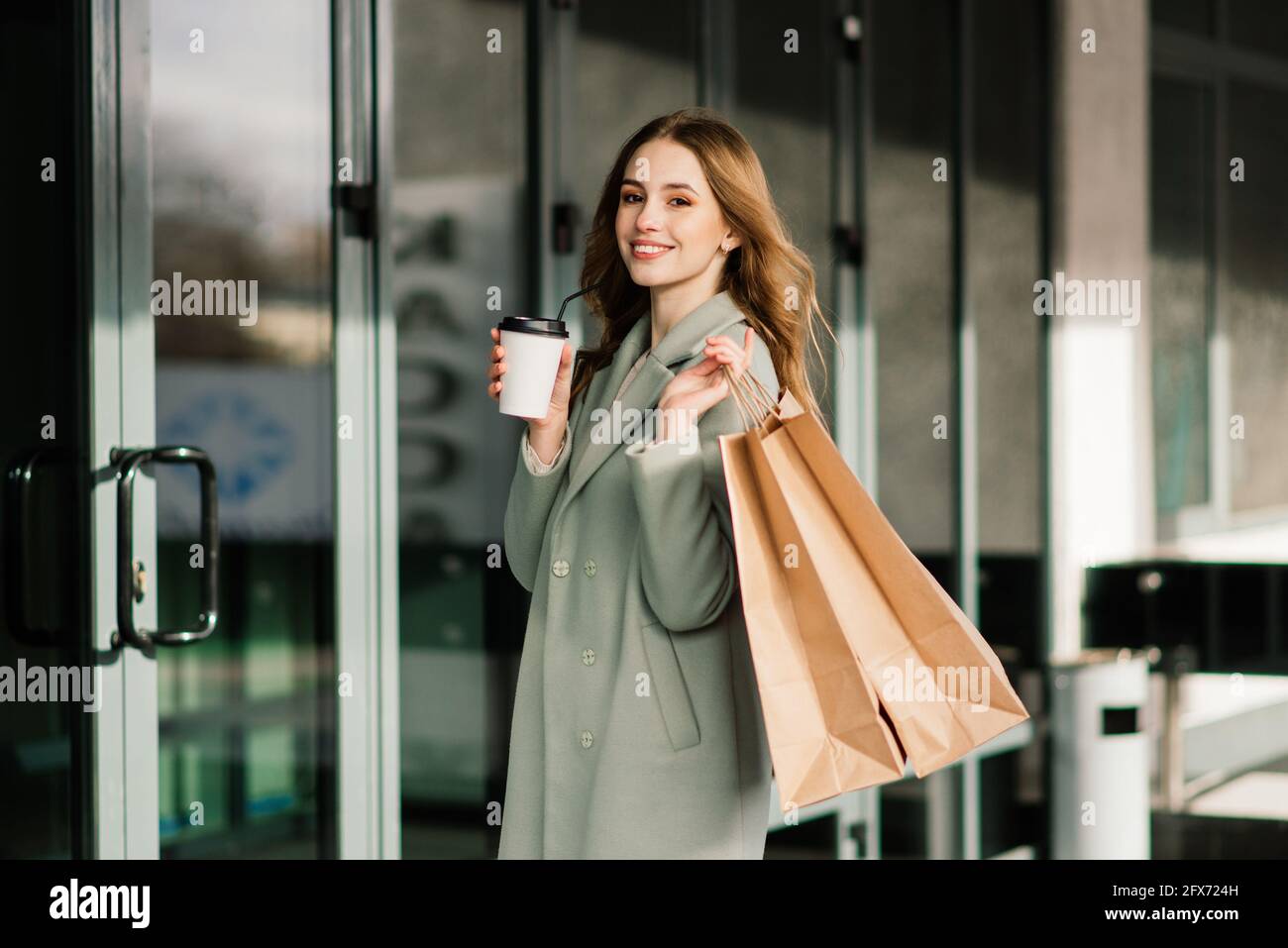 Portrait of cheerful young lady holding shopping bags outdoor Stock ...