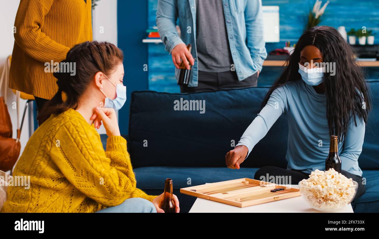Cheerful woman using dice playing backgammon with multiethnic friends ...