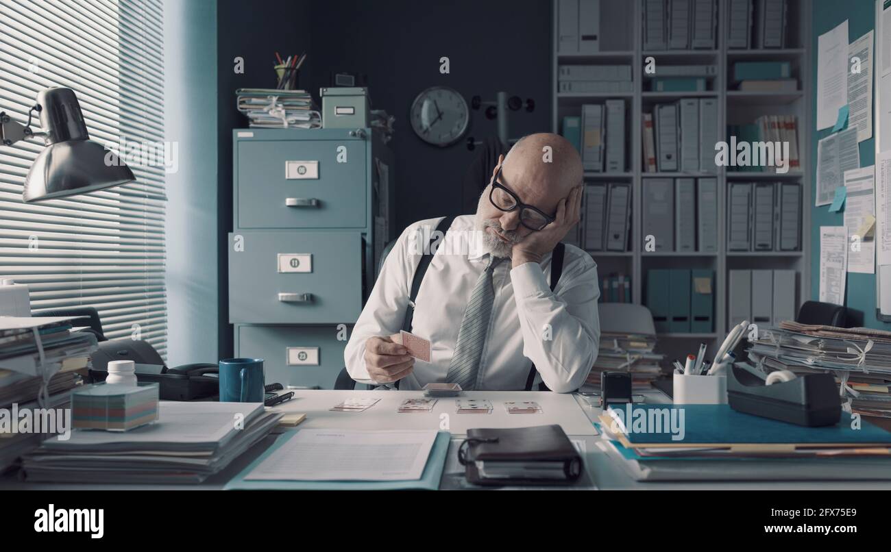 Lazy unproductive employee sitting at office desk and playing cards ...