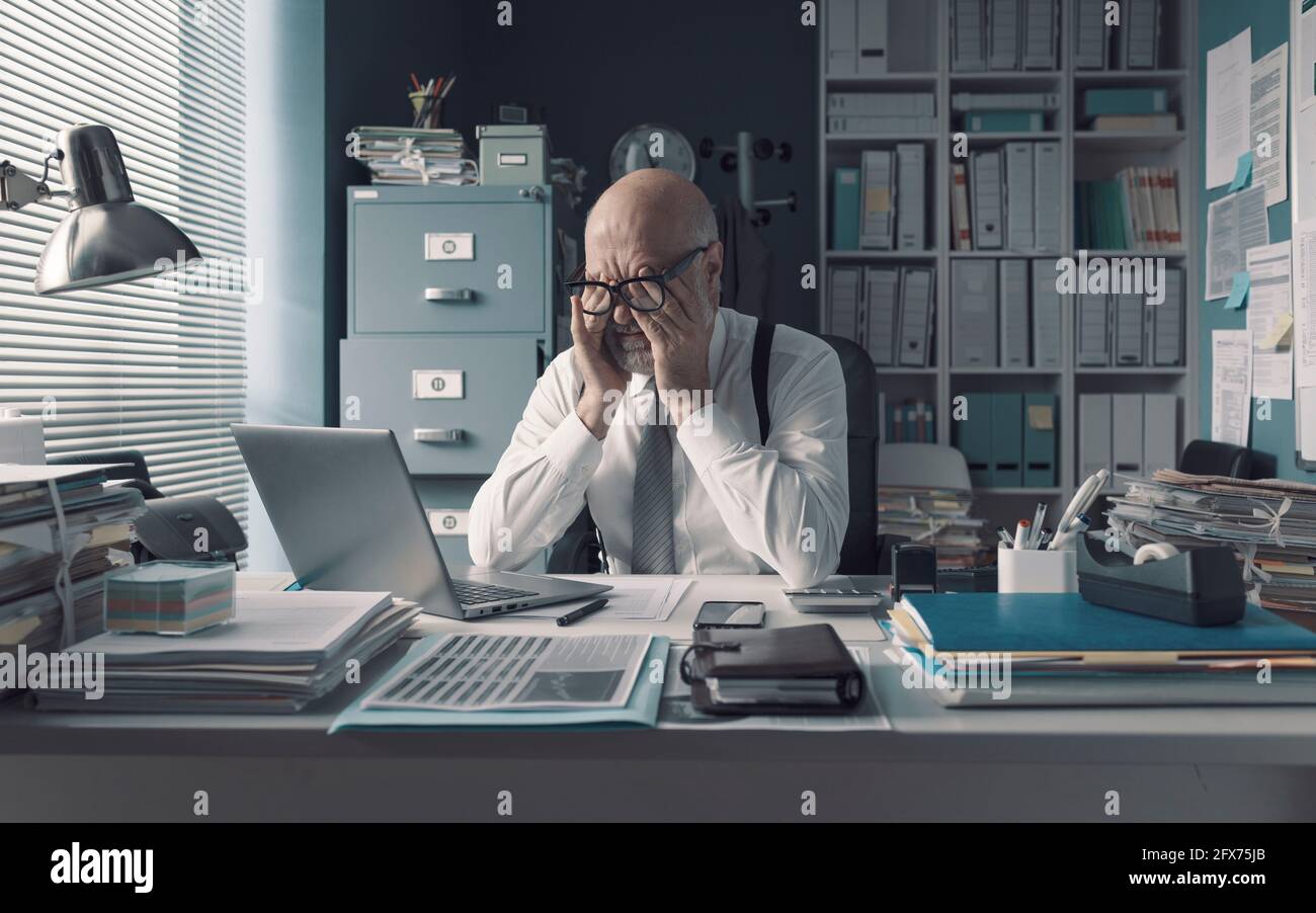 Tired stressed office worker sitting at desk and thinking, he is ...