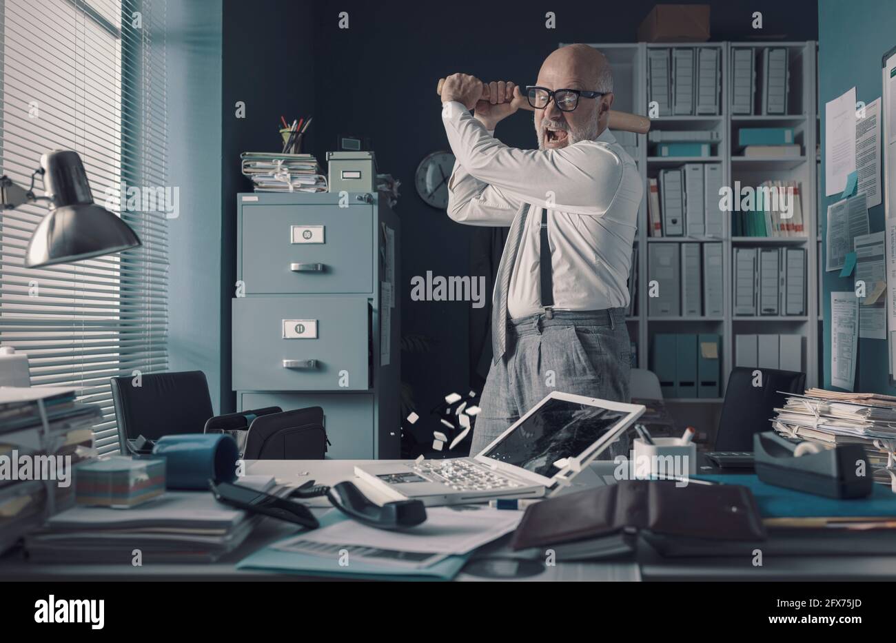 Crazy stressed businessman destroying his desk and laptop with a ...