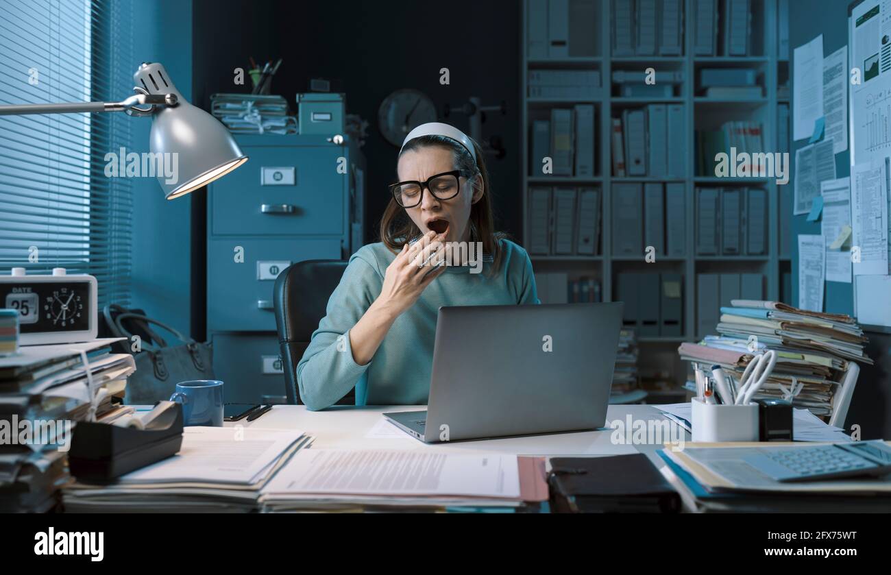 Lazy employee sitting at office desk and yawning Stock Photo - Alamy