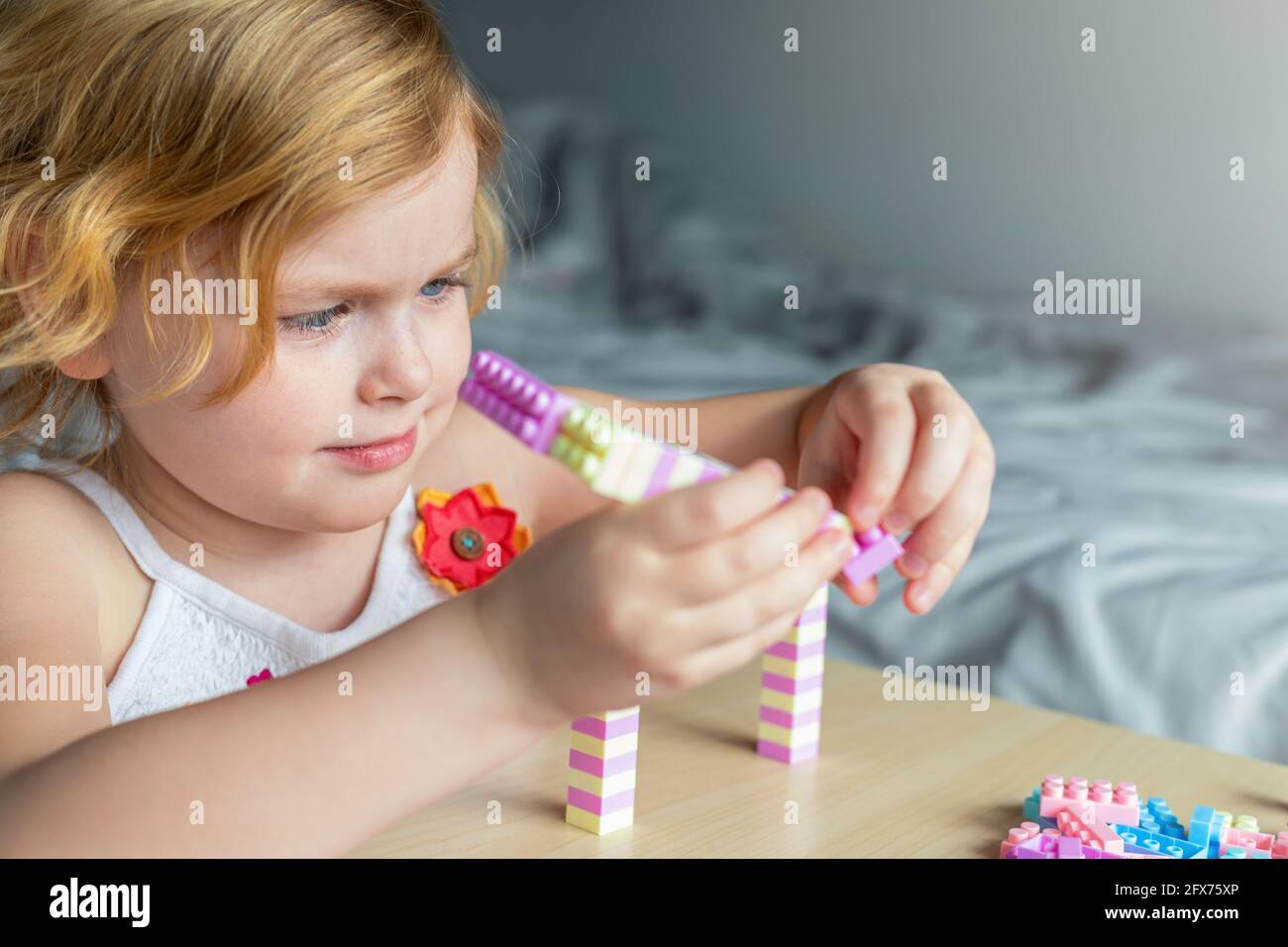 Little beautiful girl playing with toy plastic building blocks, sitting ...