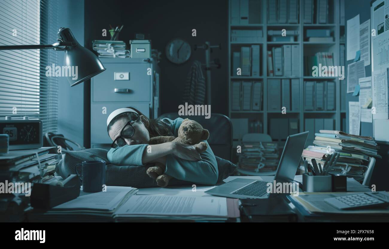 Exhausted young office worker sleeping at her desk, job burnout and ...