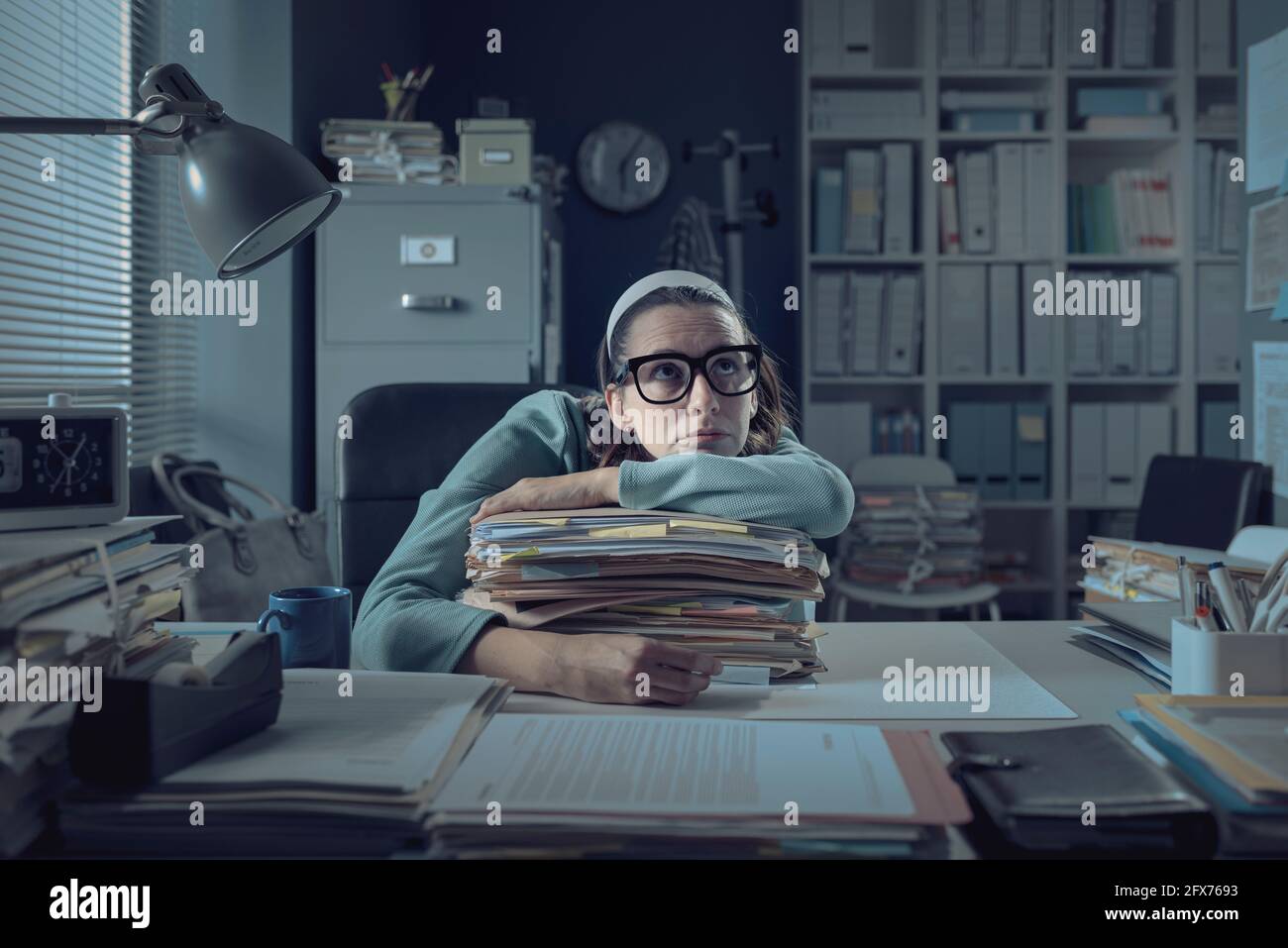 Frustrated tired office worker leaning on a pile of paperwork and ...