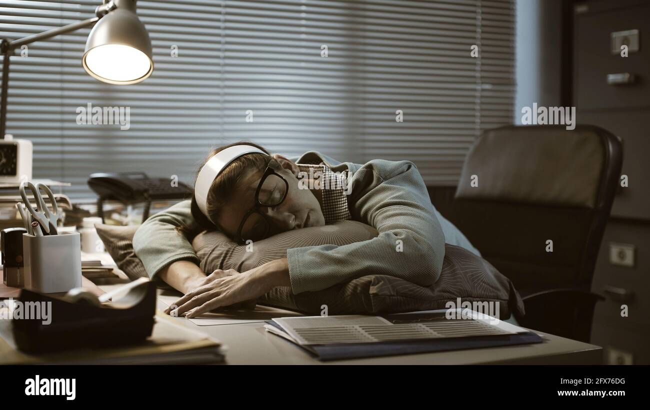 Exhausted young office worker sleeping at her desk, job burnout and ...