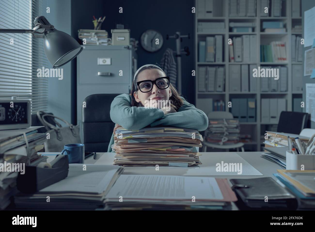 Lazy office worker sitting at desk and leaning on a pile of paperwork ...