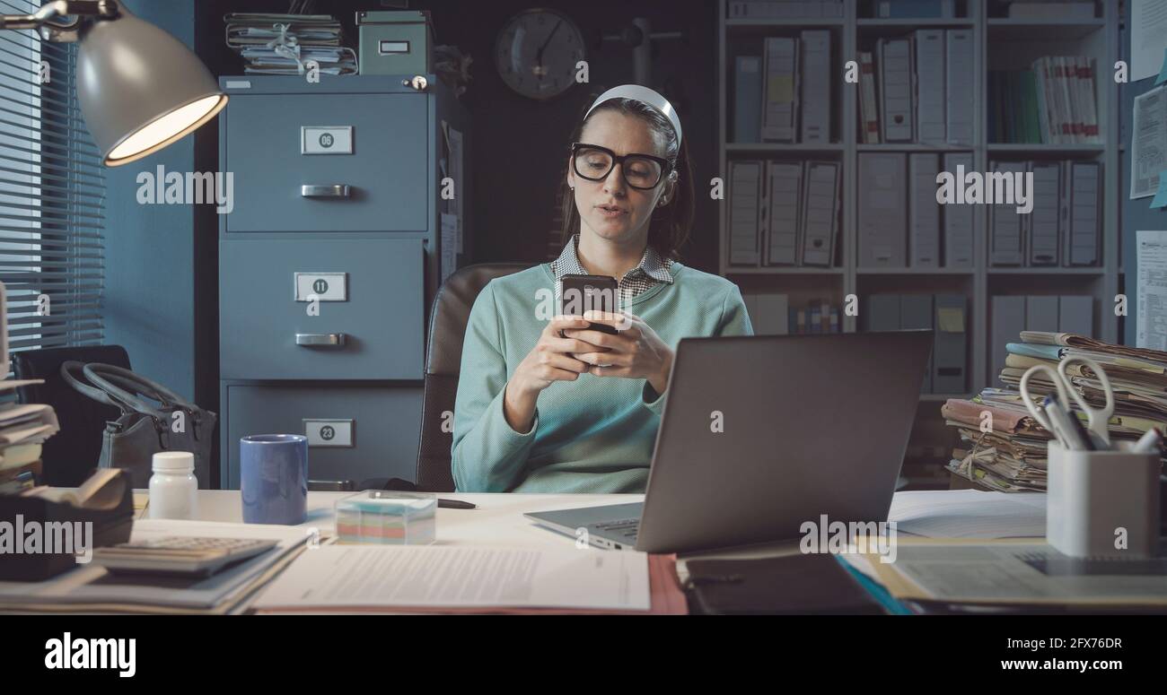 Inefficient office worker sitting at desk and chatting with her phone ...