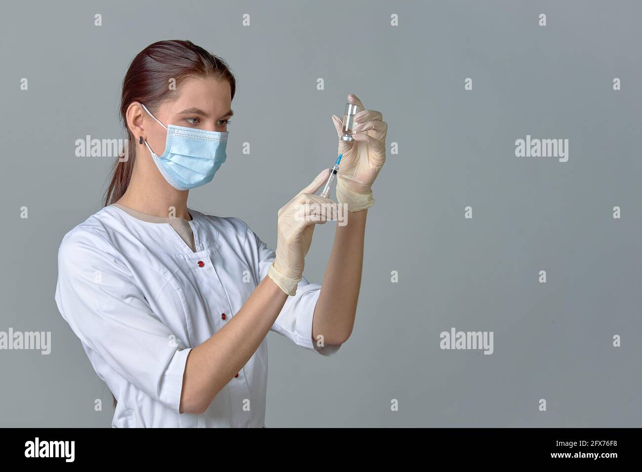 A nurse taking medicine into a syringe from a bottle close-up, a place ...
