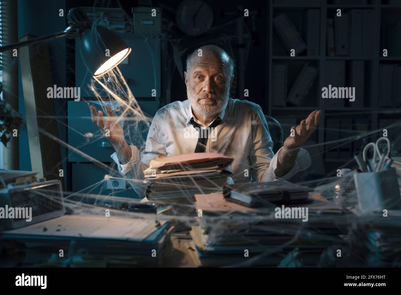 Confused corporate businessman sitting at desk in a abandoned dusty ...