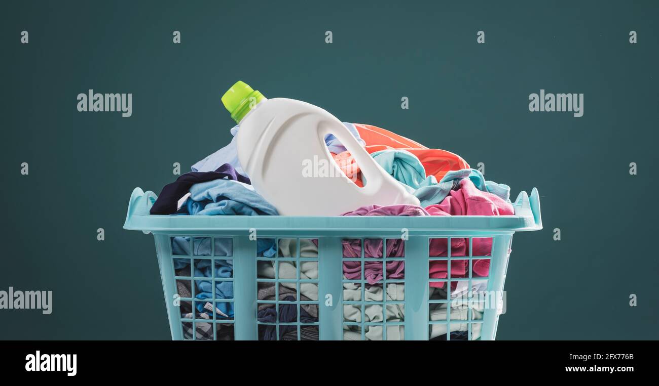 Green detergent and clothes in a laundry basket: eco-friendly laundry ...