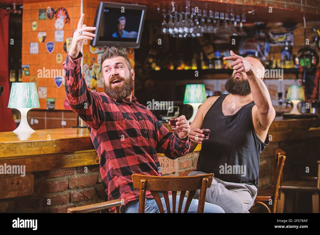 Hipster brutal bearded man drinking alcohol with friend at bar counter ...
