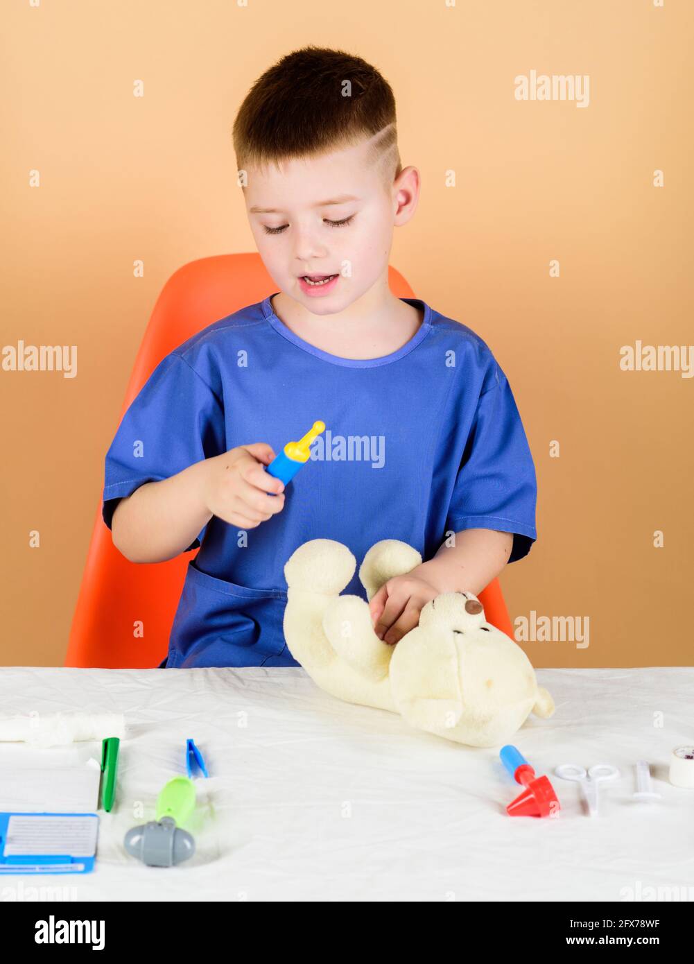 Kid little doctor busy sit table with medical tools. Medicine concept ...