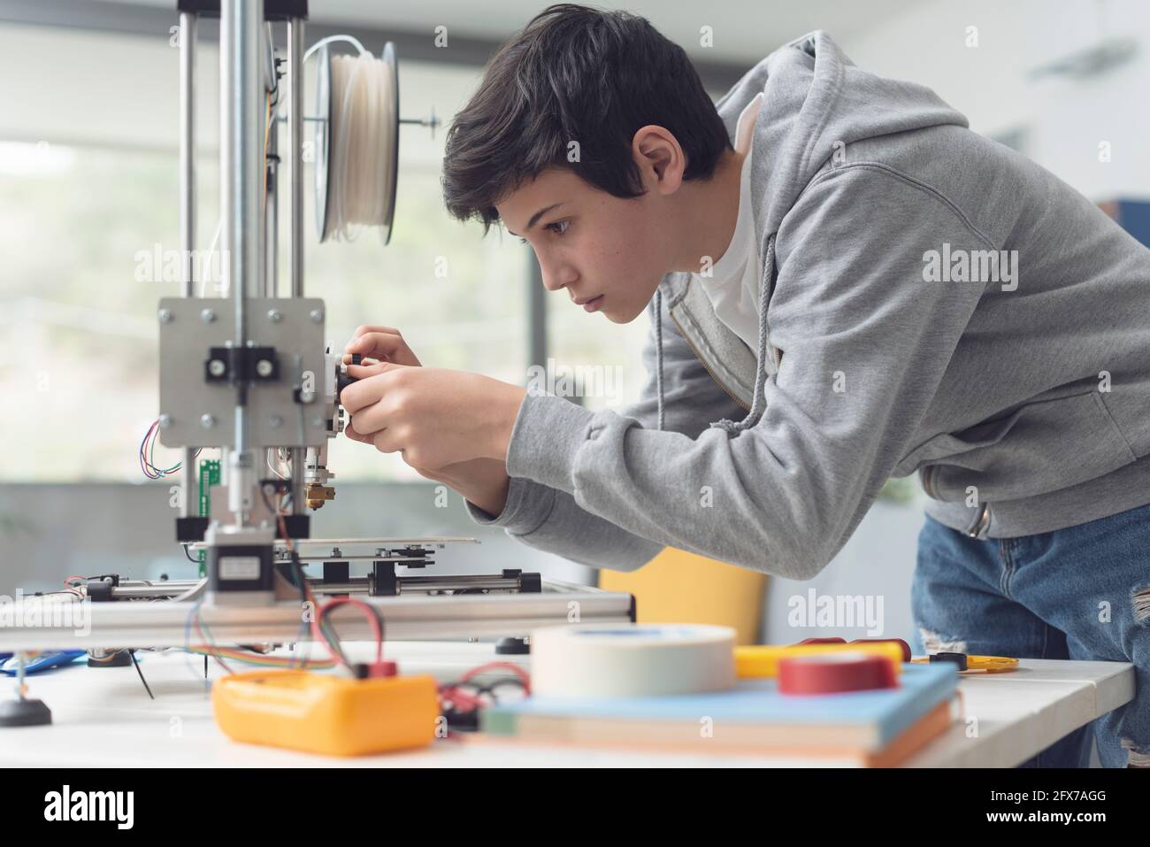 Smart young student learning 3D printing, he is checking the printer ...