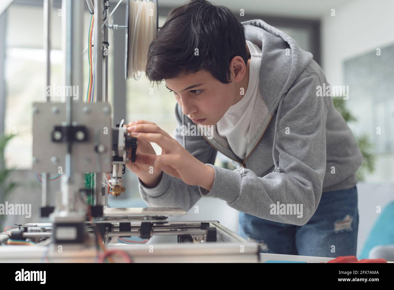 Smart young student learning 3D printing, he is checking the printer ...