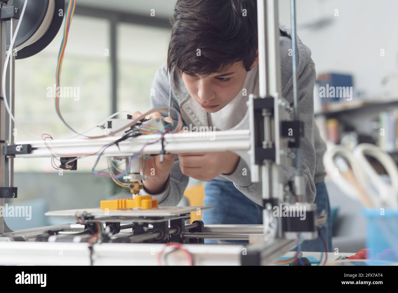 Smart young student learning 3D printing, he is checking the printer ...