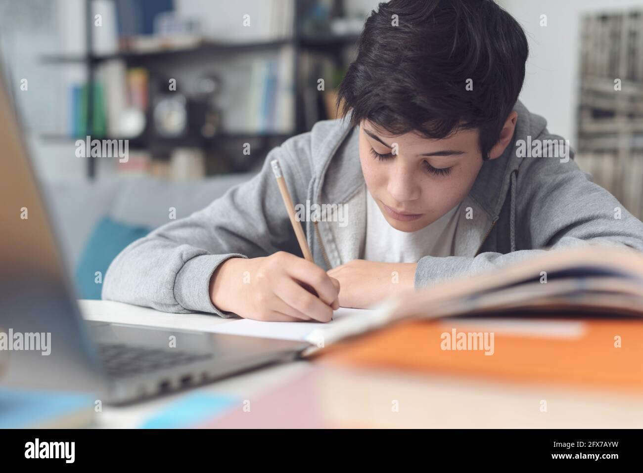 Focused student doing his homework at home, he is writing notes and ...