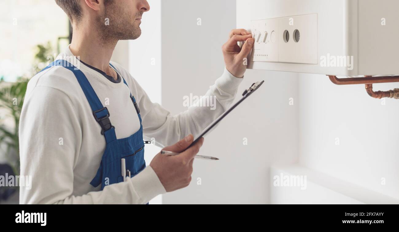Professional plumber checking a boiler control panel, he is adjusting a ...