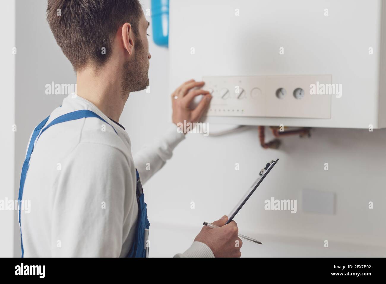 Professional plumber checking a boiler control panel, he is adjusting a ...