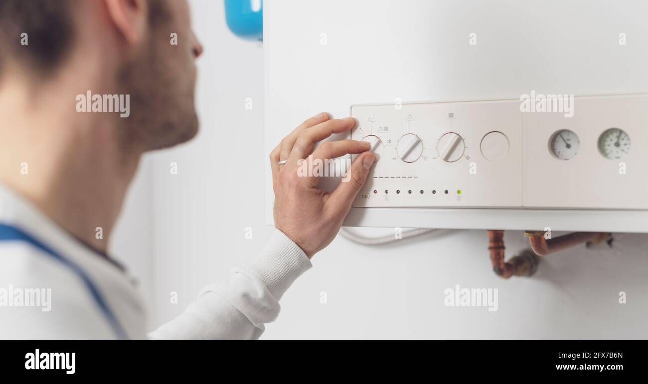 Professional plumber checking a boiler control panel, he is adjusting a ...