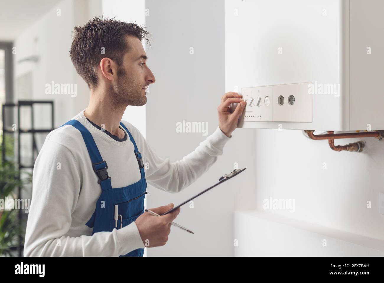 Professional plumber checking a boiler control panel, he is adjusting a ...