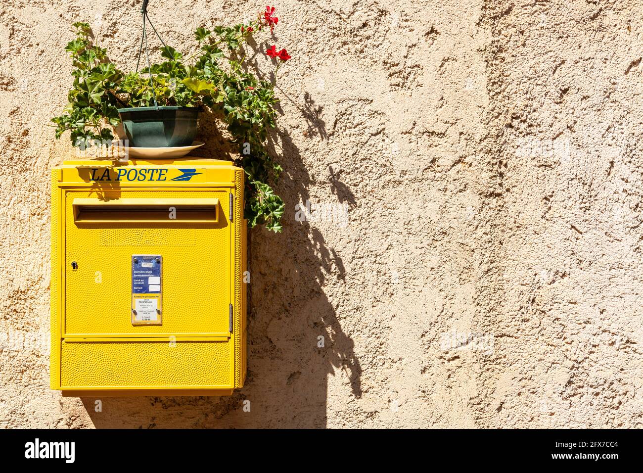 Yellow post box La Poste française, with a pot of flowers Stock Photo ...