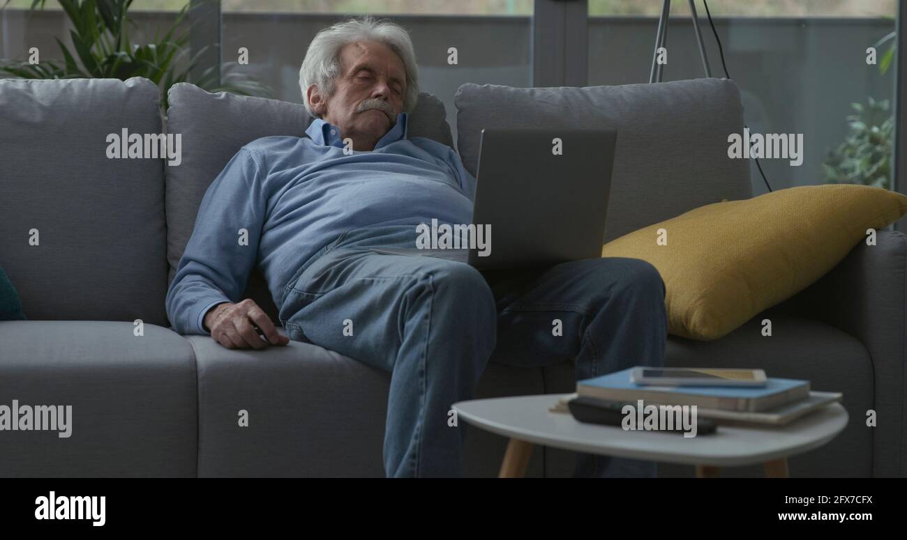 Elderly man falling asleep on the couch while watching videos on his ...