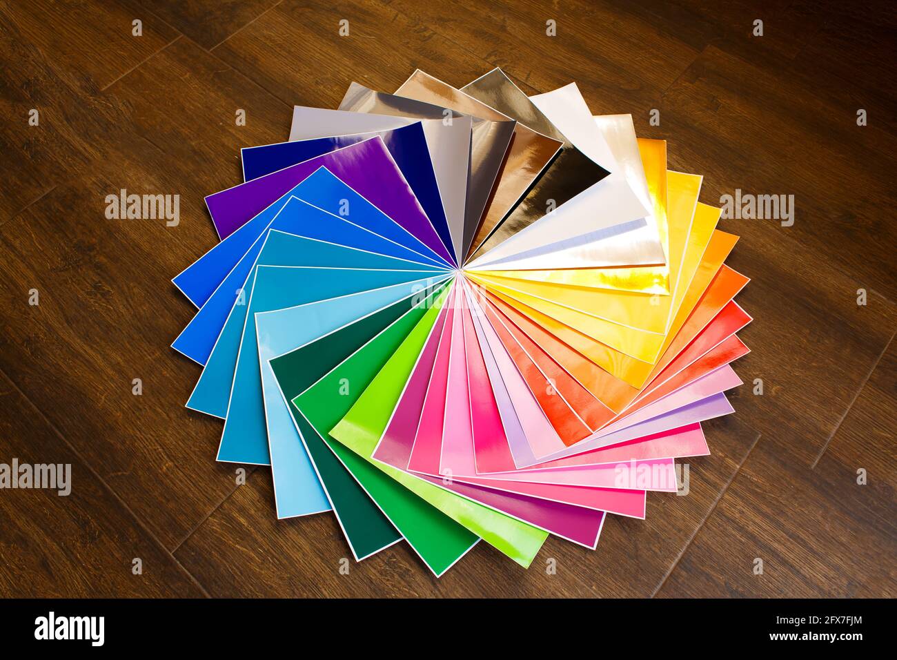 Twisted pile of colorful 12x12 sheets of adhesive paper on brown ...
