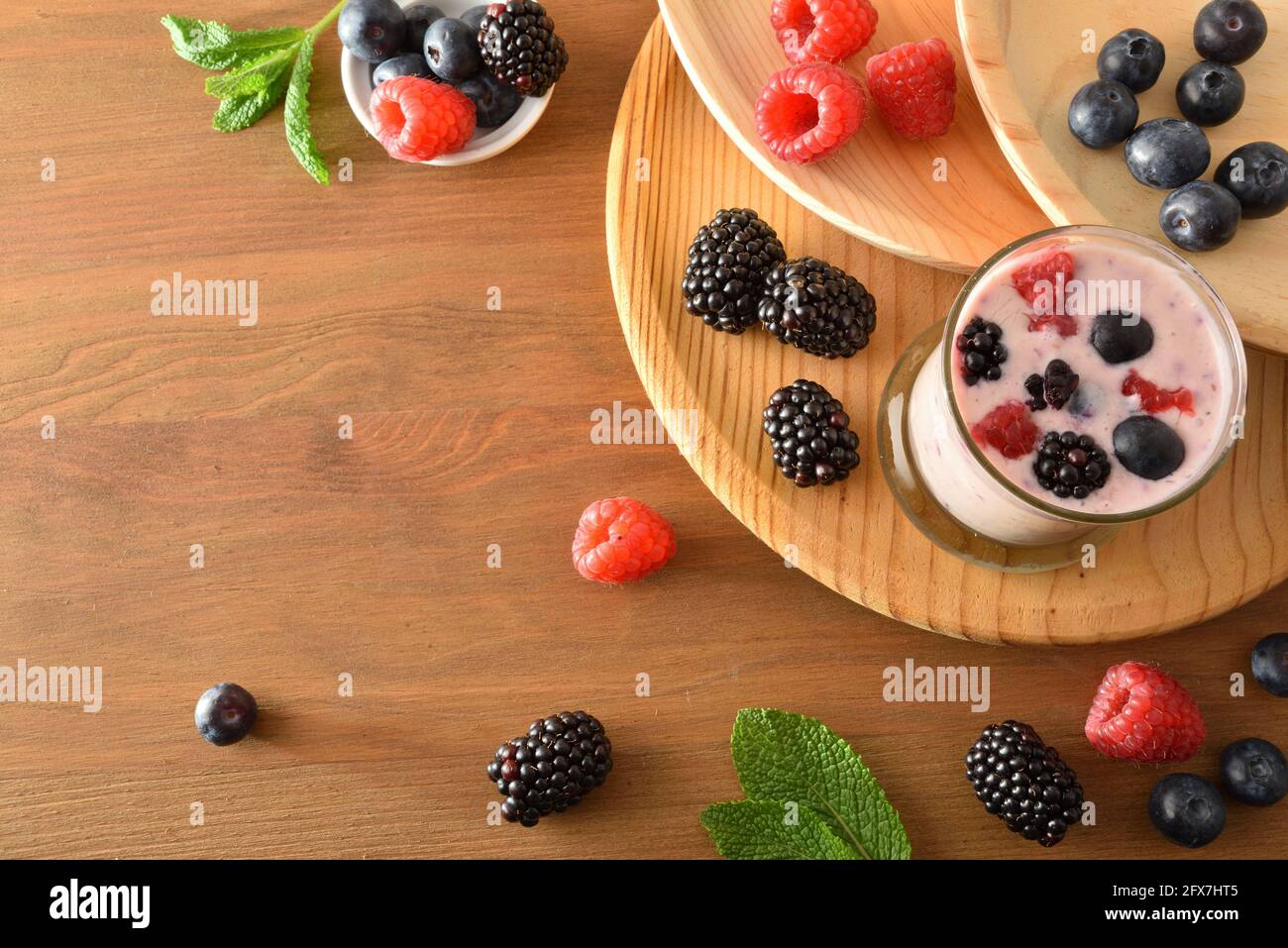 Forest fruit smoothie yogurt in glass and fruits on wooden bench. Top ...