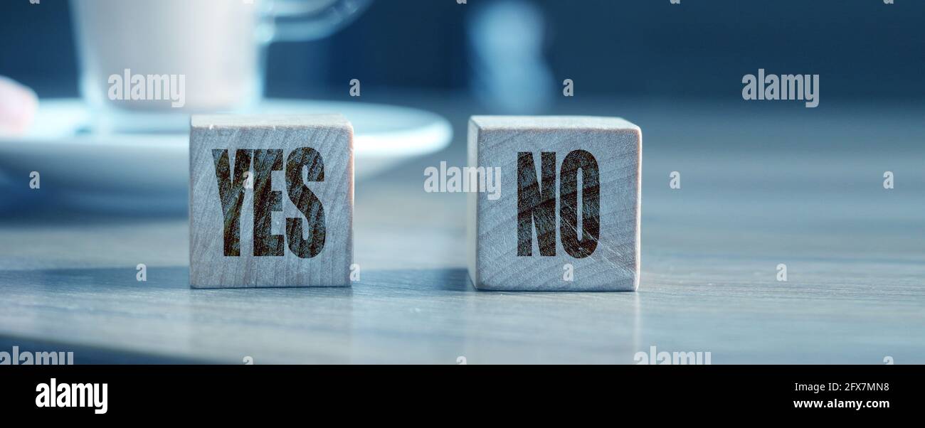Yes versus no wooden cubes in front of cacao cup on table. Business ...