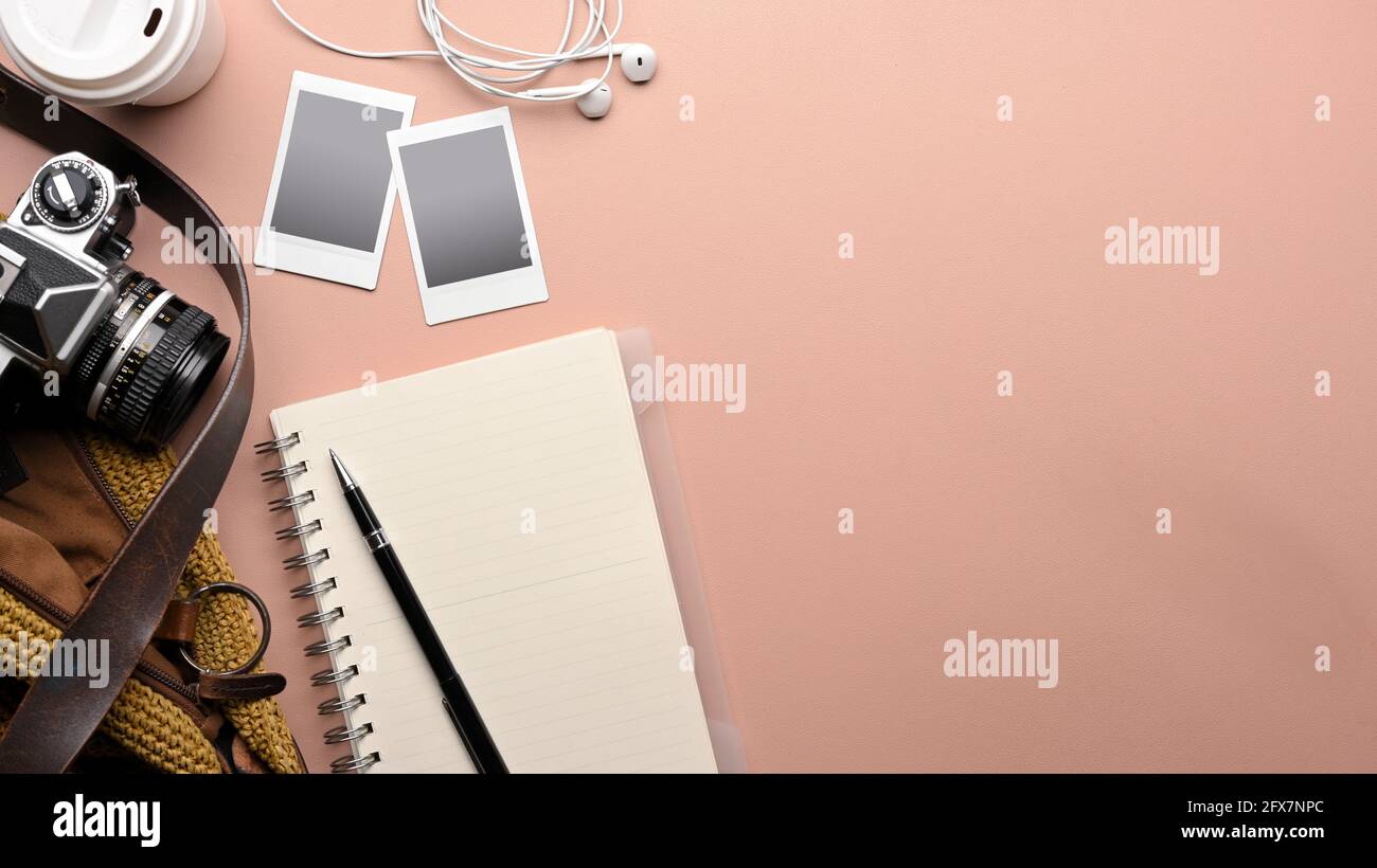 Top view of pink table with notebook, pen, camera, photo frame, bag and ...