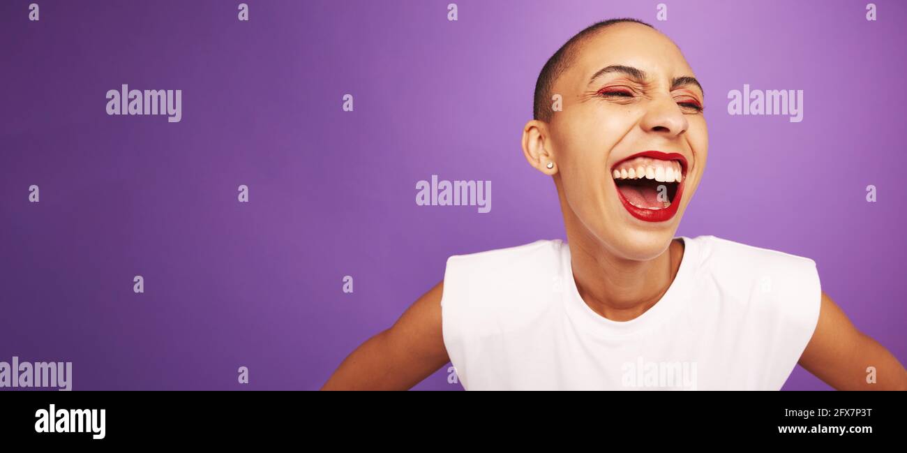 Closeup of a woman with short hairstyle laughing on purple background ...