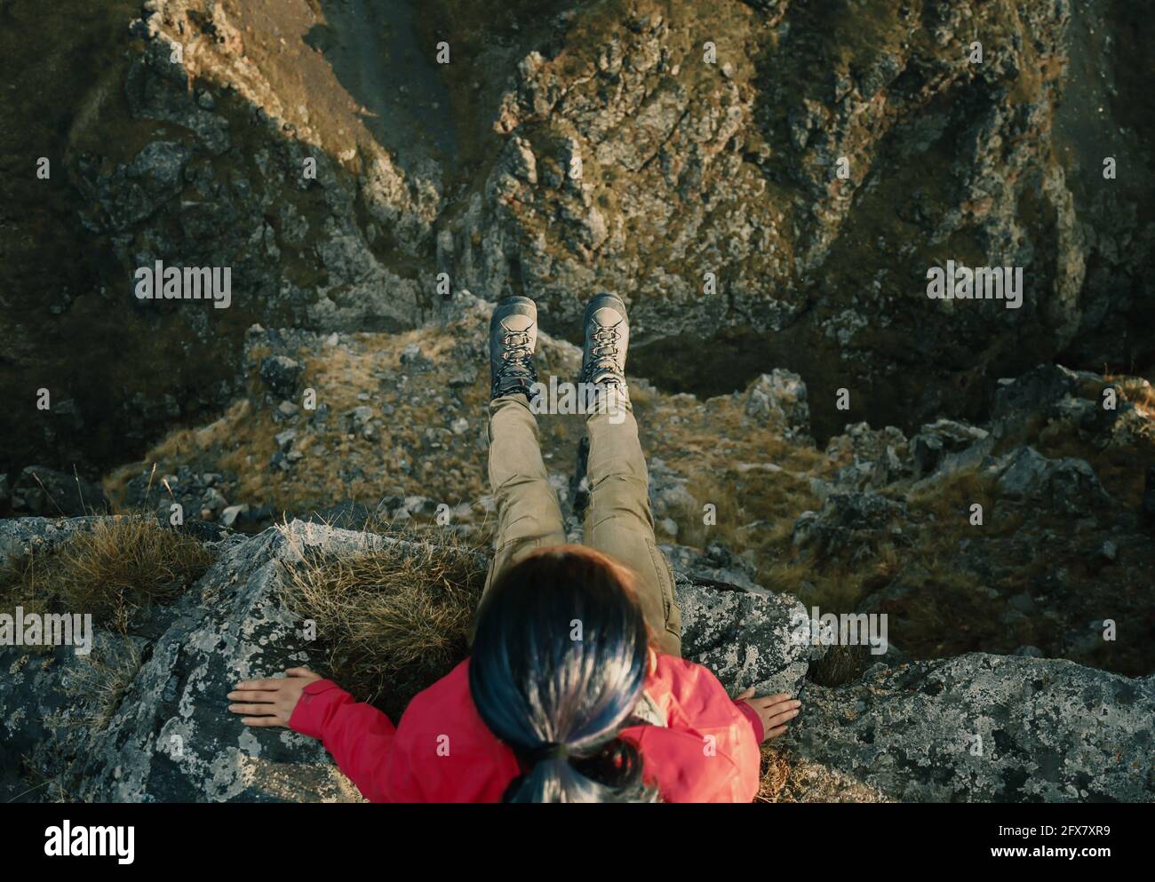 Woman sitting on edge of cliff Stock Photo - Alamy