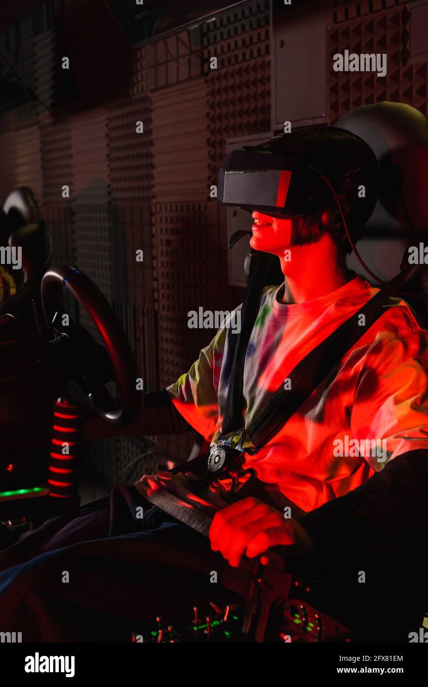 smiling teenager playing racing game on car simulator Stock Photo - Alamy