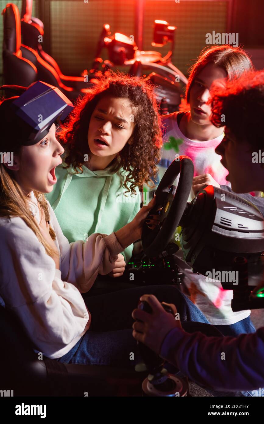 worried multiethnic friends looking at scared girl screaming on racing ...