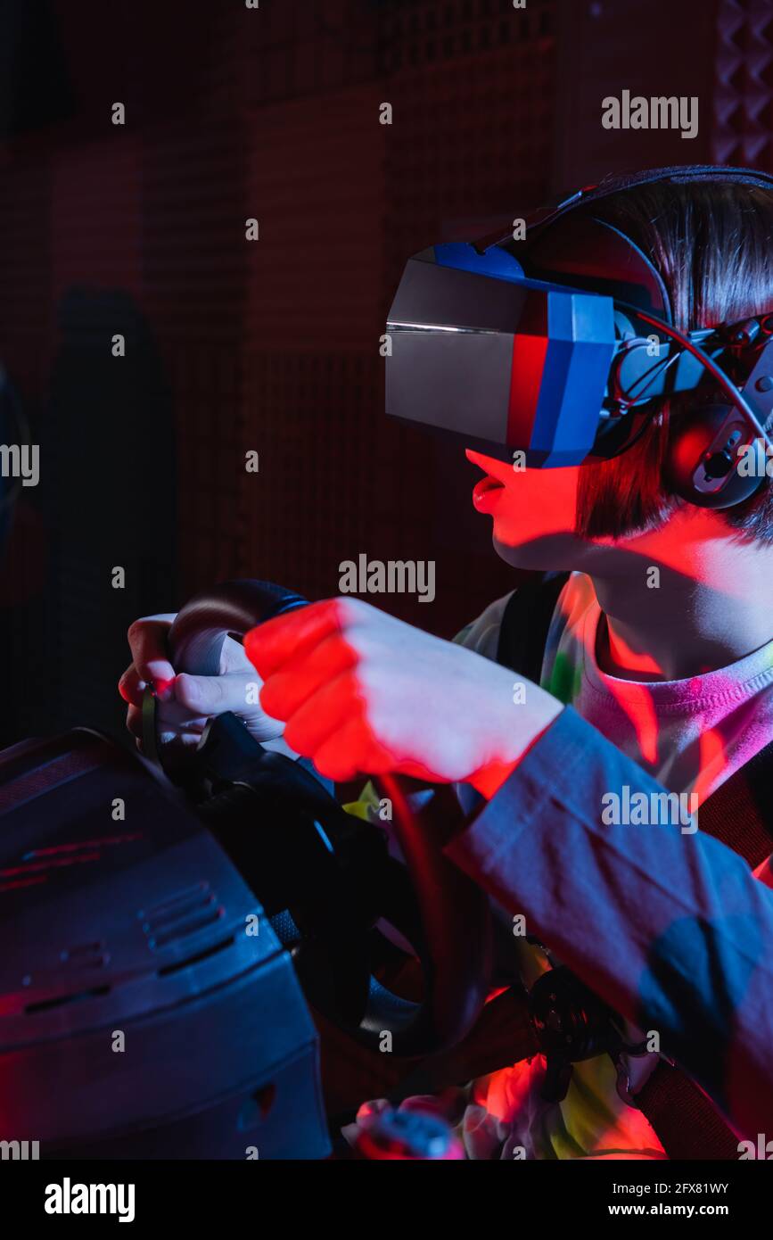amazed boy in vr headset gaming on car racing simulator with open mouth ...