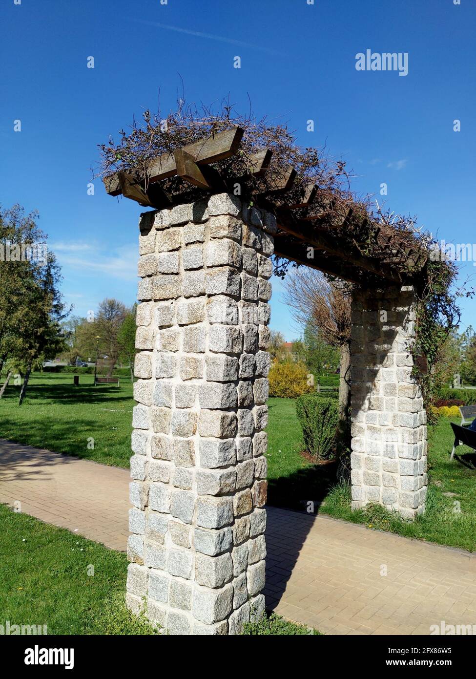 Vertical shot of two brick pillars in a park with a paved road going ...