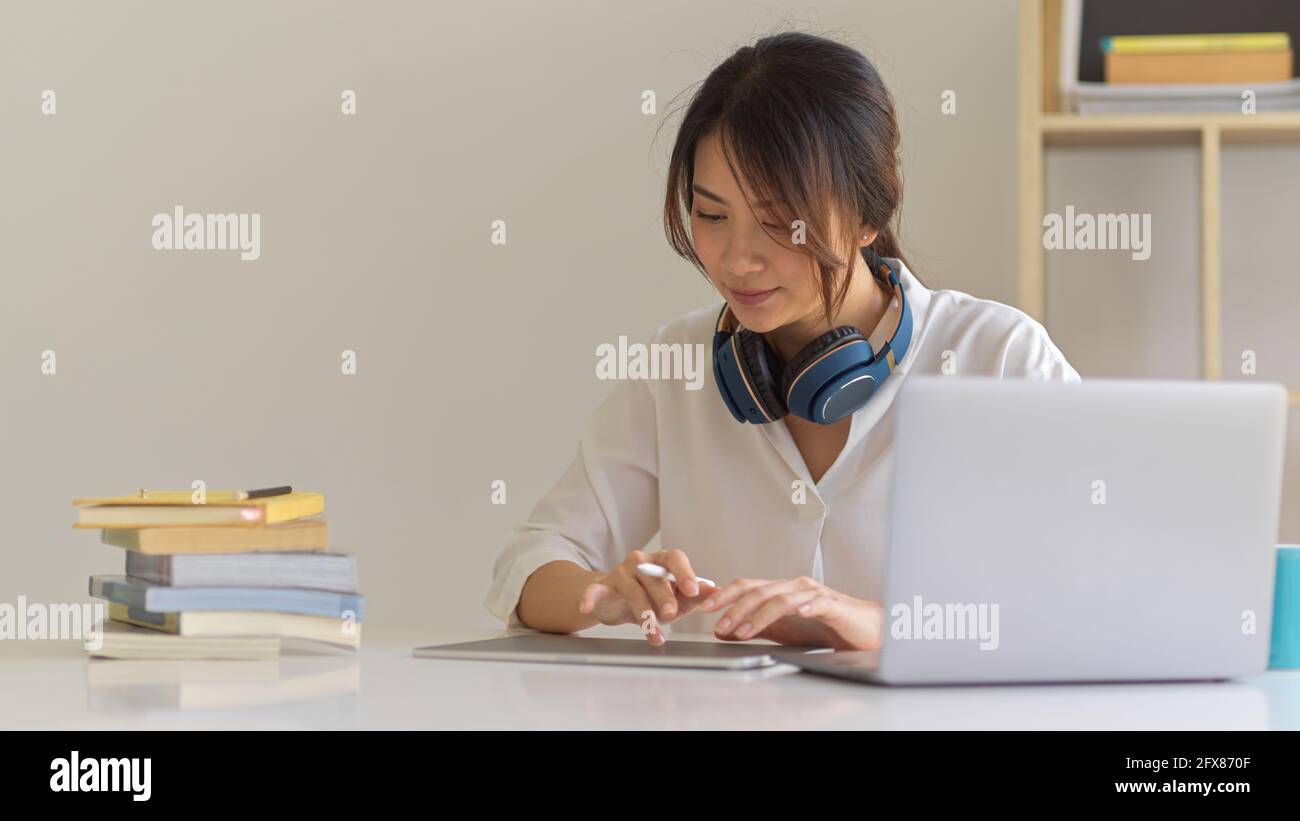 Portrait of female student concentrating on her assignment with digital ...